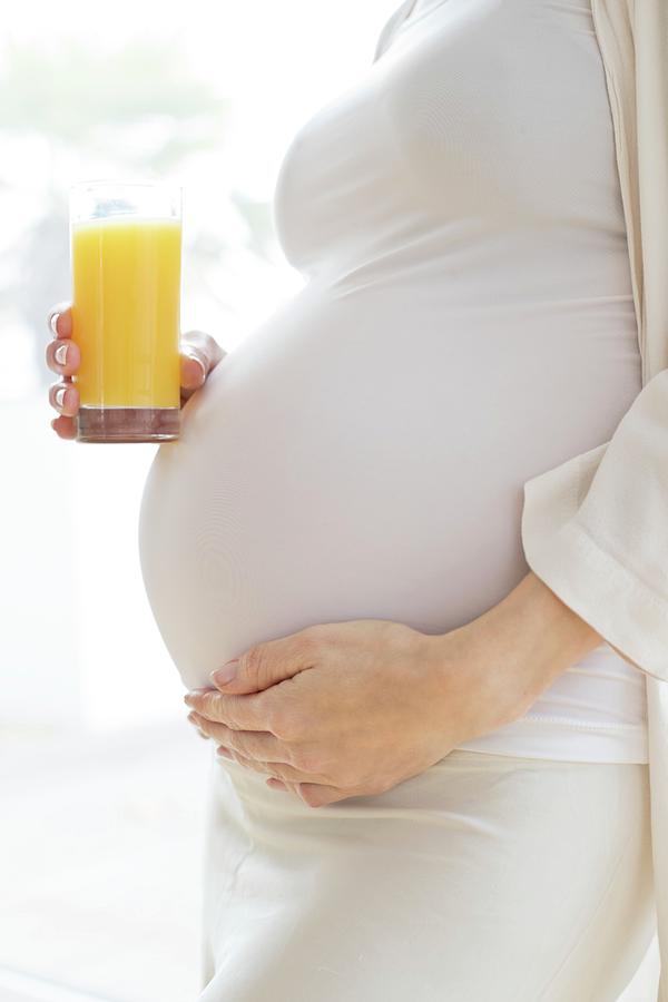 Pregnant Woman Touching Tummy With Juice Photograph By Ian Hooton