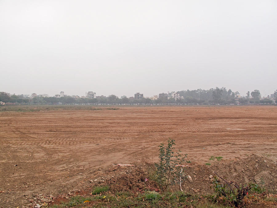 A Wide Open Dusty Field Surrounded By Cars And Trees And Buildings ...
