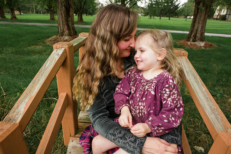 Close Up Of Daughter Sitting On Mothers Lap At Park Photograph By