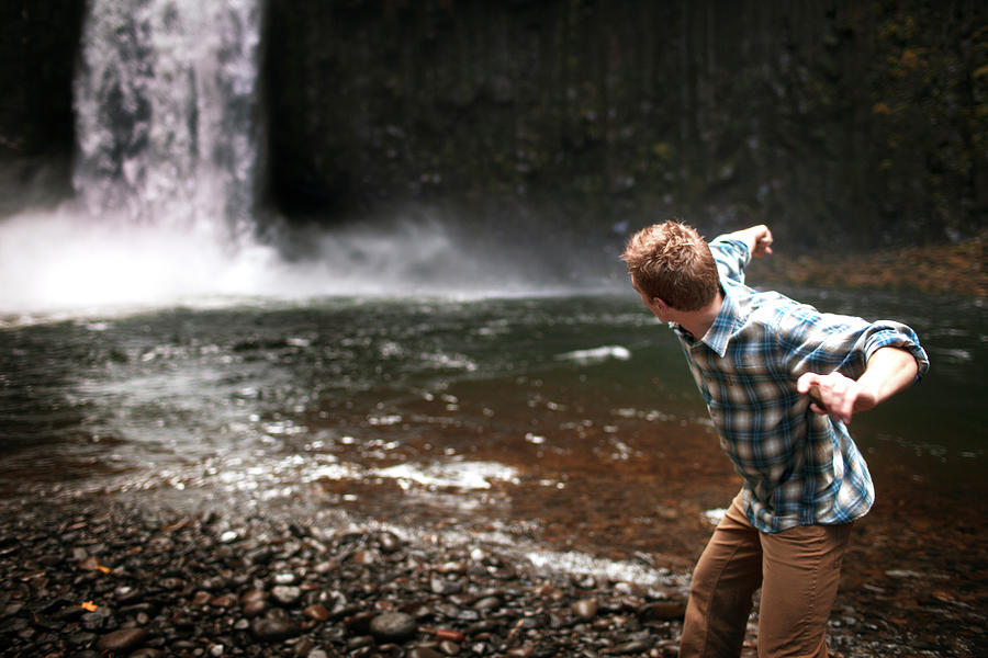 Man Throwing Stone At Waterfall Photograph by Cavan Images - Fine Art ...