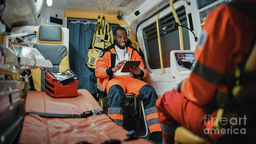 Paramedic Using Tablet Computer While Riding In Ambulance Photograph by ...