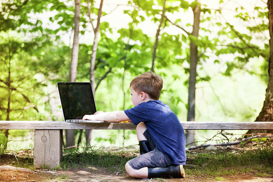 Side View Of Boy Using Laptop Computer At Concrete Bench Photograph by ...