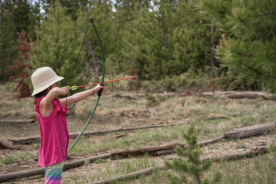 Side View Of Girl Aiming With Bow And Arrow While Standing Against ...