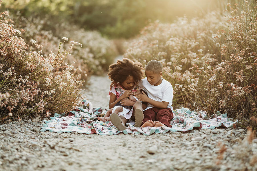 Three Happy Siblings Sitting On Blanket In Flower Field Together ...
