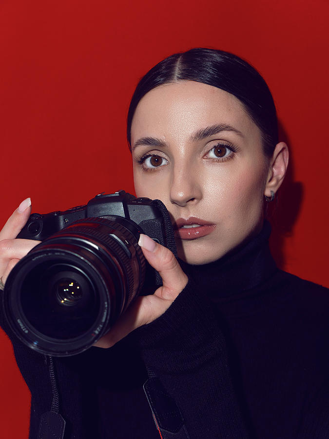 Portrait Brunette Woman Photographer With A Camera On A Red Background