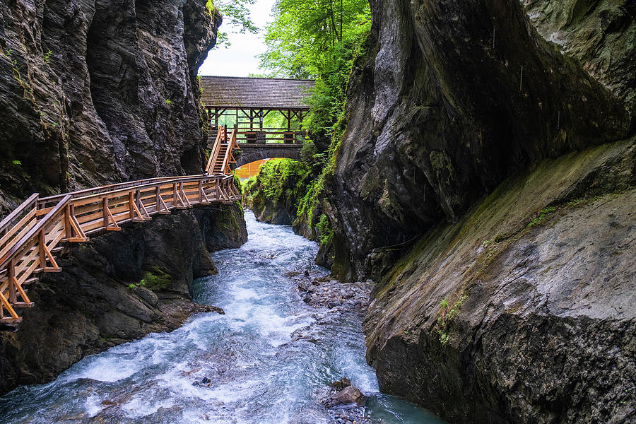A beautiful gorge in the Alps with a wooden path on the side and a ...