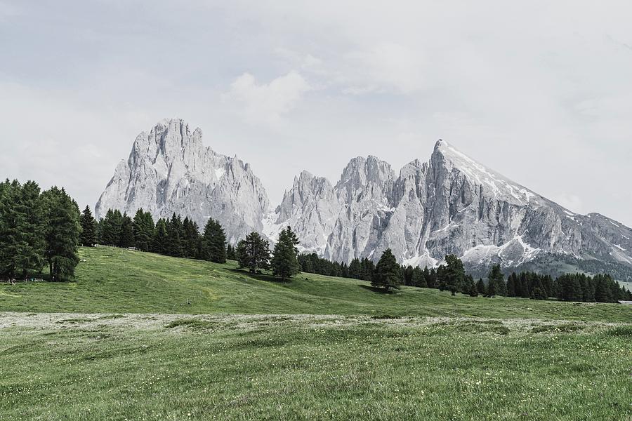 green grass field near gray rocky mountain under white cloudy sky ...