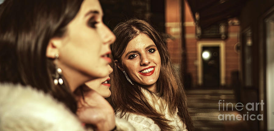 Three women in furry winter coats and heavy makeup stand in alley talk ...