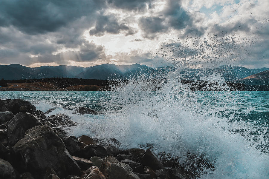 Water crashing against rocks with the sunset over the mountains ...